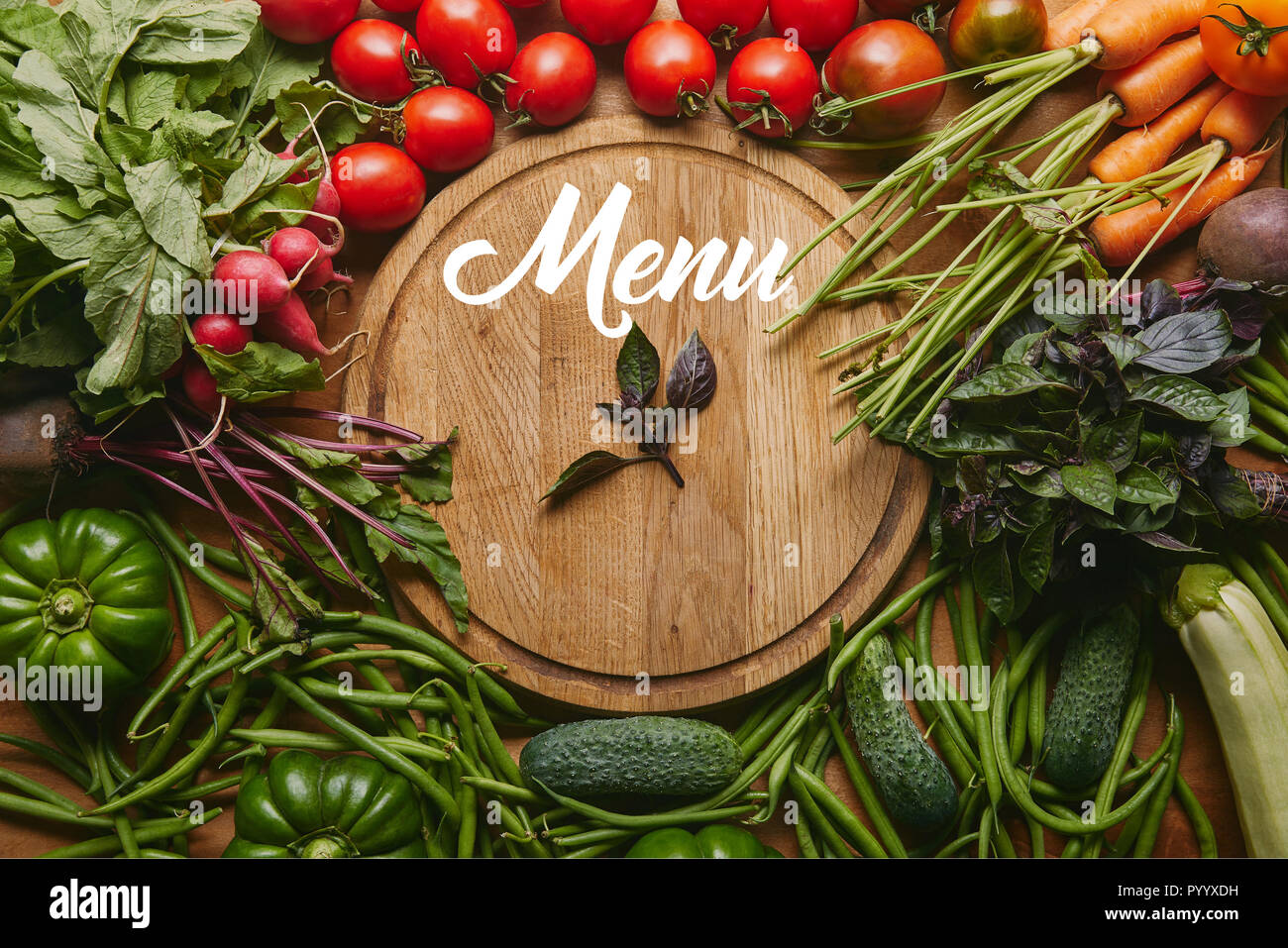 Variety of fresh vegetables and herbs by cutting board with "menu ...