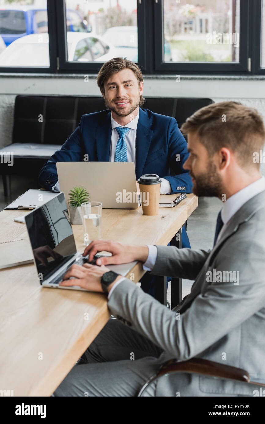 young businessmen in suits using laptops and working together in office ...