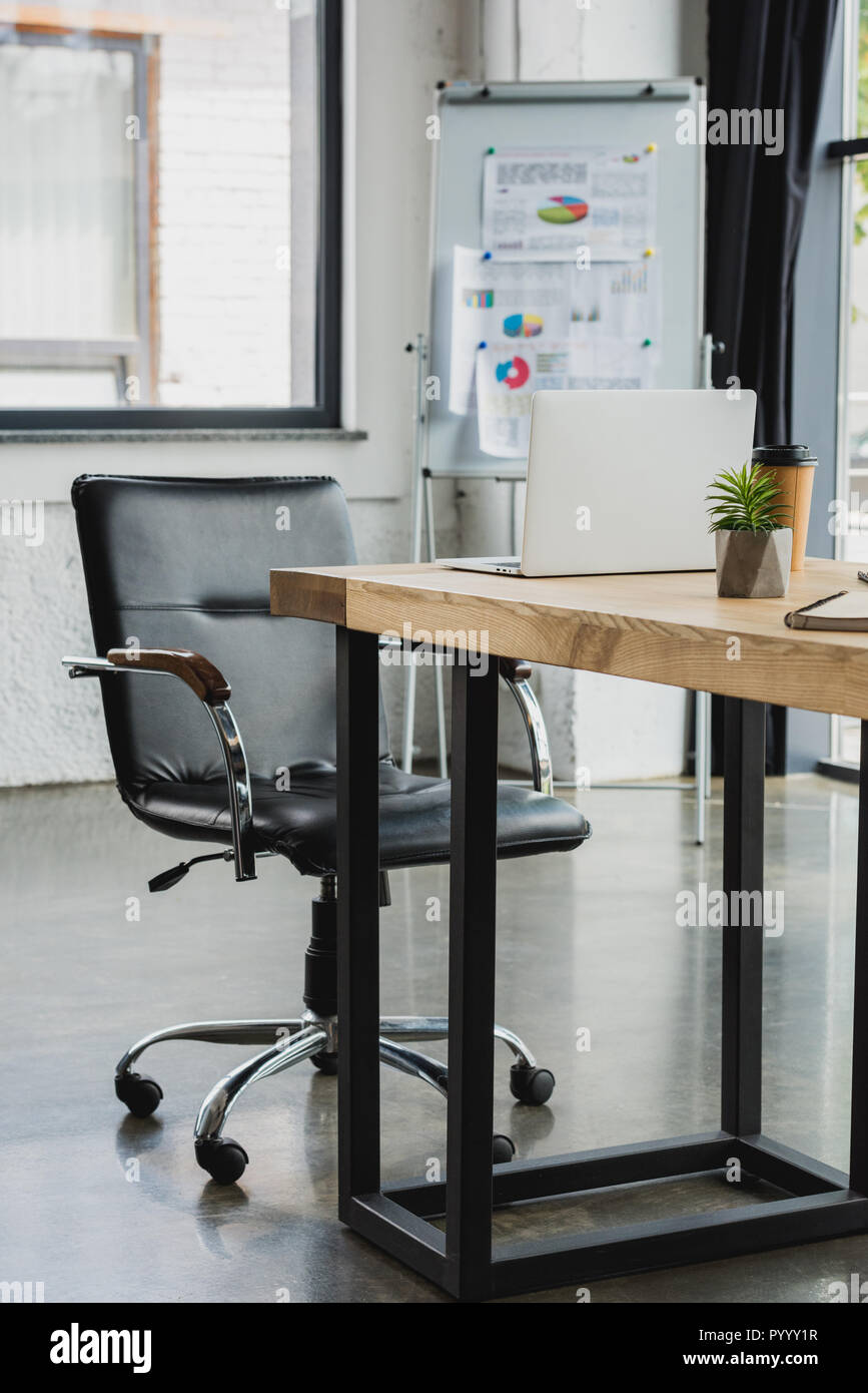 laptop on table and whiteboard with business charts in modern office ...