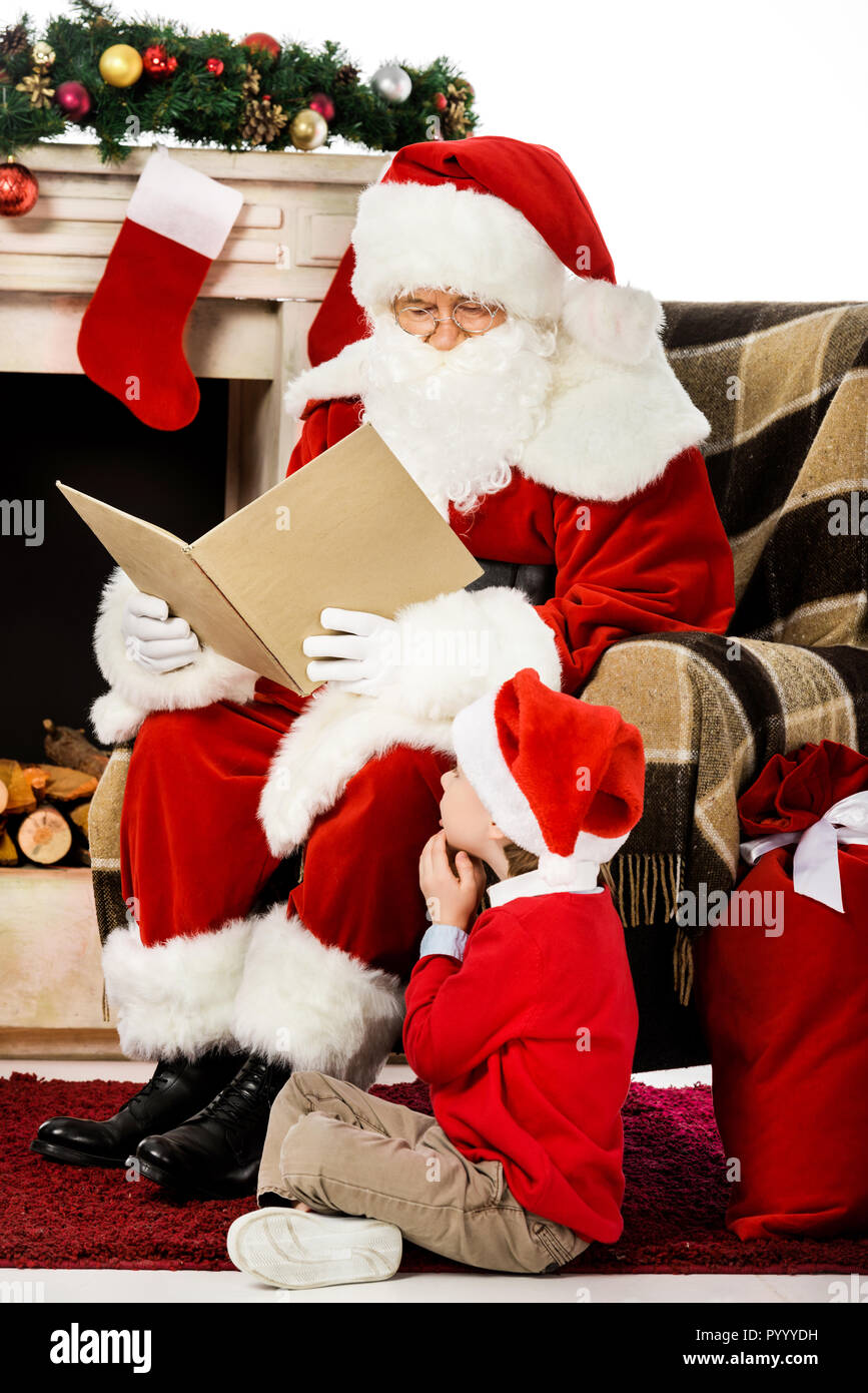 santa reading book to little kid while he sitting on carpet Stock Photo ...