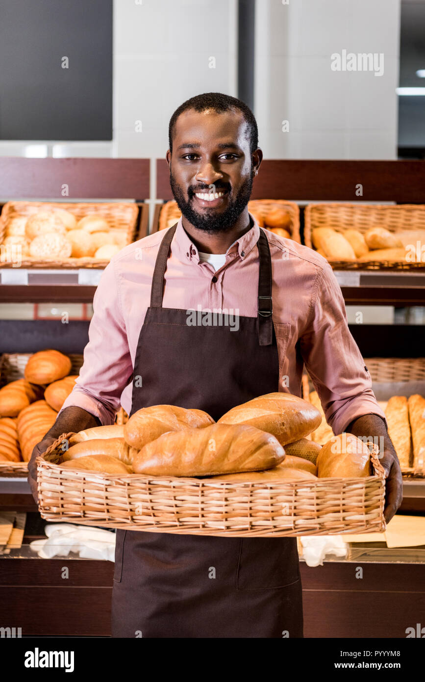 smiling african american male shop assistant in apron holding with ...