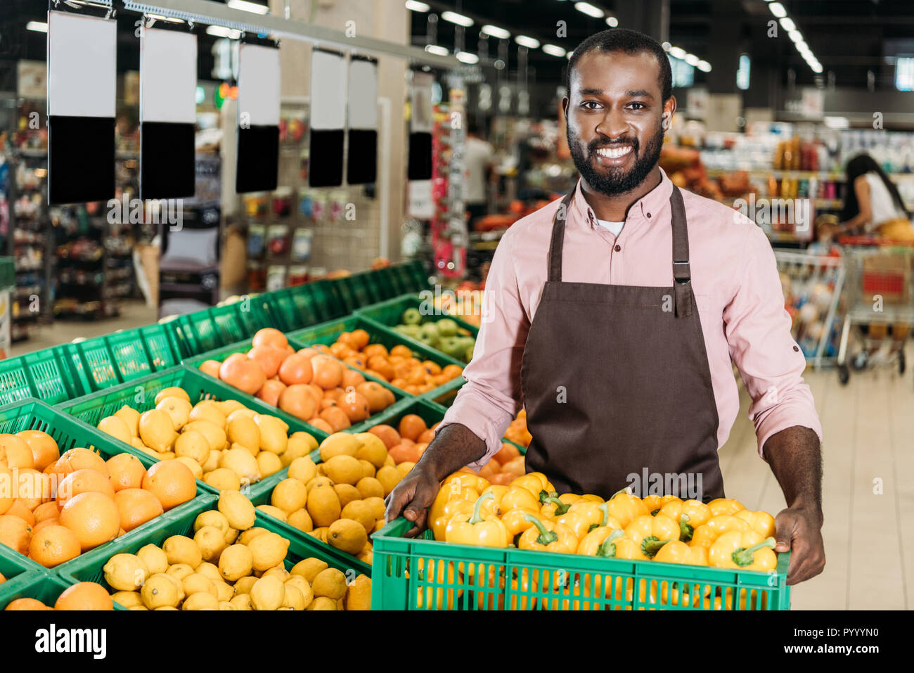 happy african american male shop assistant in apron holding box with ...