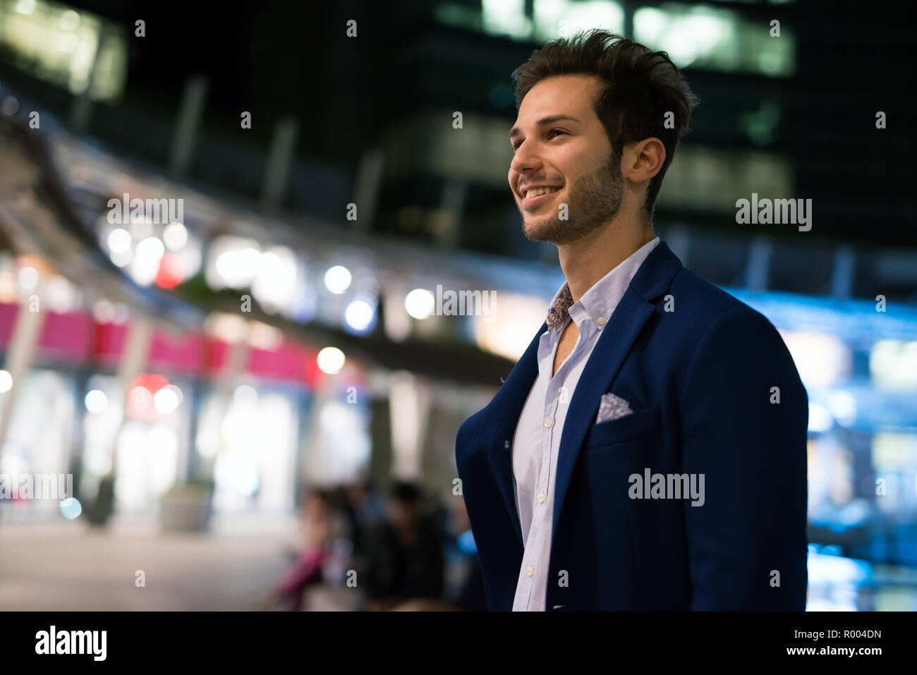 Smiling young man walking outdoors at night Stock Photo - Alamy