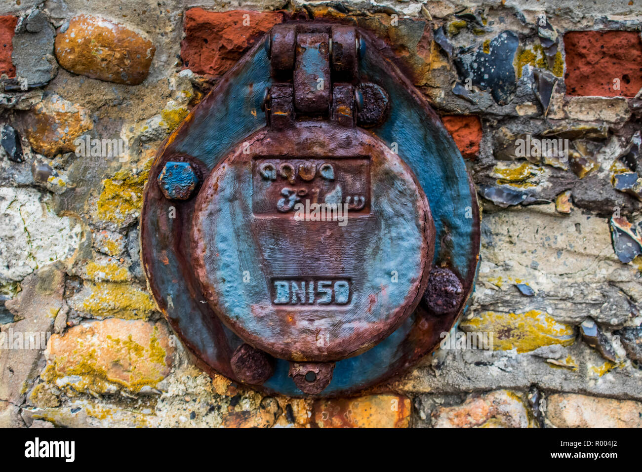 A colourful Water outlet or water overflow in a flint and brick wall ...