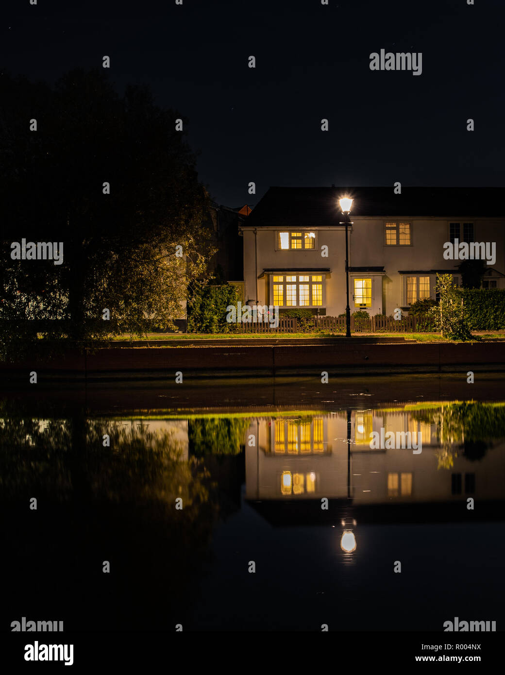 Cozy English Cottages at night lit by street lamp with reflections in ...