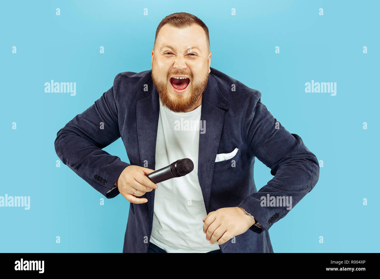 Young man with microphone on blue studio background, leading concept ...