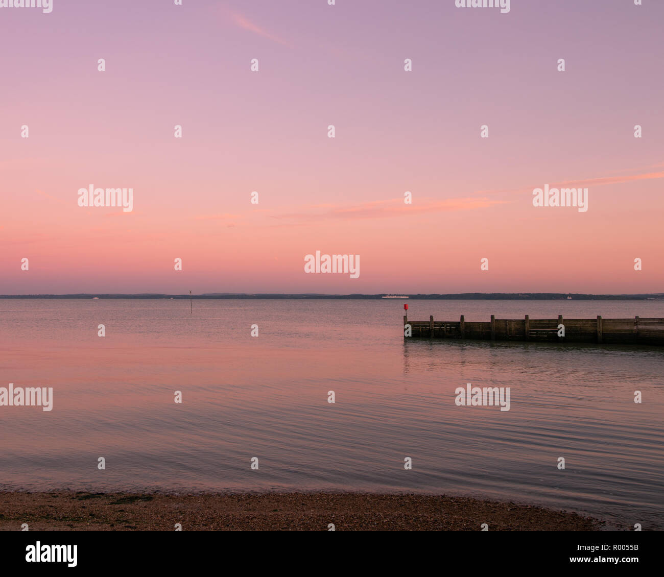 very calm seas at sunset with wooden beach groynes Stock Photo - Alamy