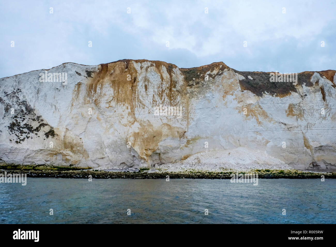 Tall white chalk cliff face, at the bottom of the cliff is a large ...