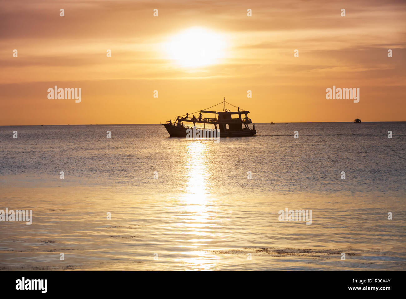 sunset in the ocean with glowing sky and lonely boat Stock Photo - Alamy