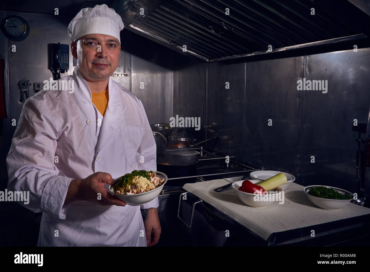 Professional chef cook in a white apron and cooks hat prepairing ...