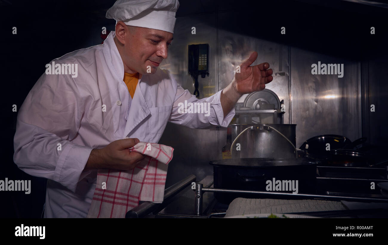Professional chef cook in a white apron and cooks hat prepairing ...