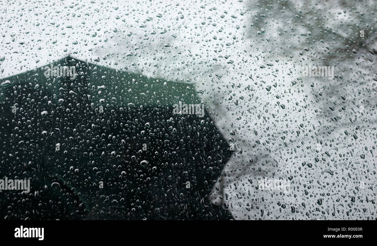 rainy weather reflections in car window. man with an umbrella under ...