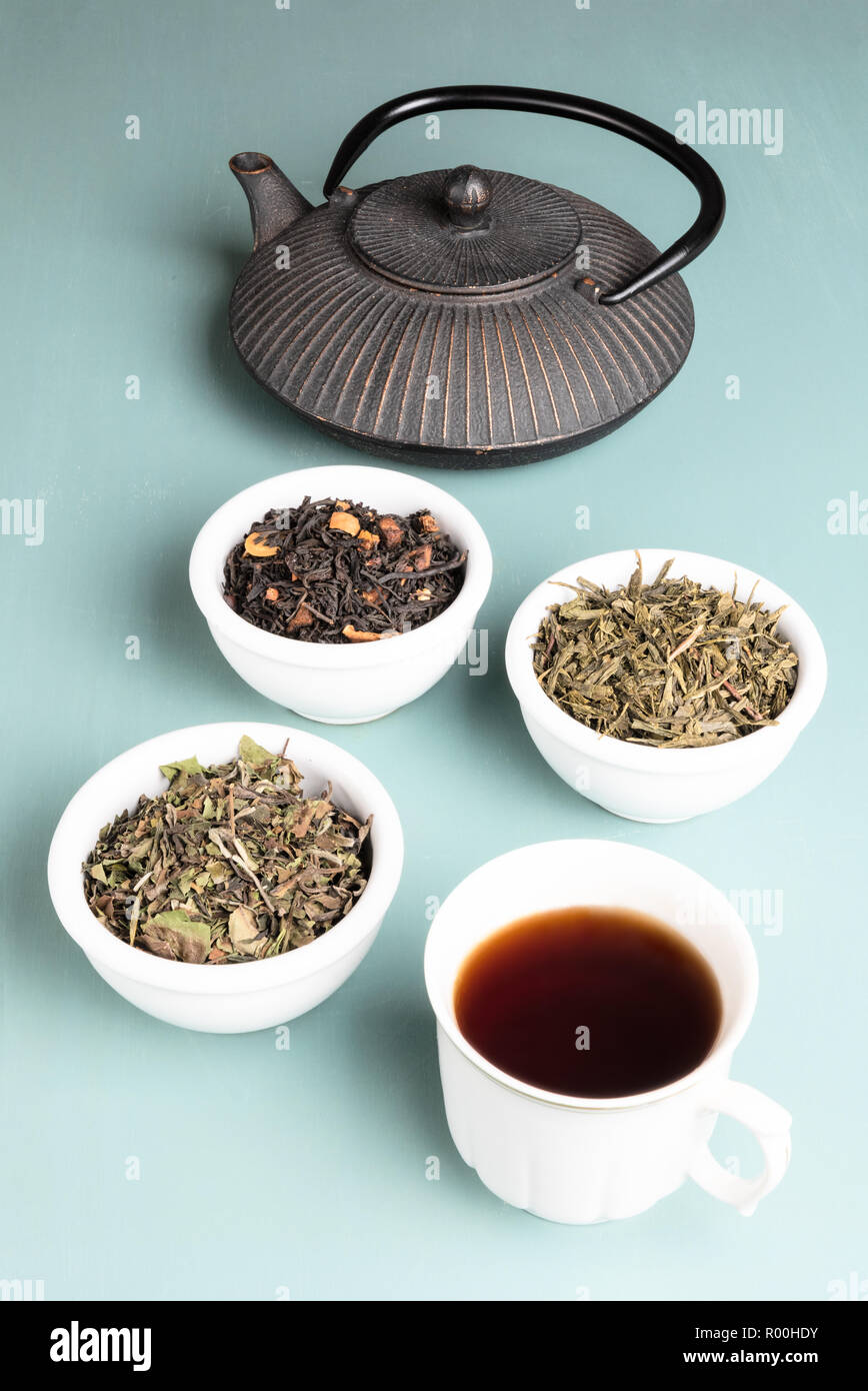 Cast iron teapot with tea cup and three bowls of black tea, bancha ...