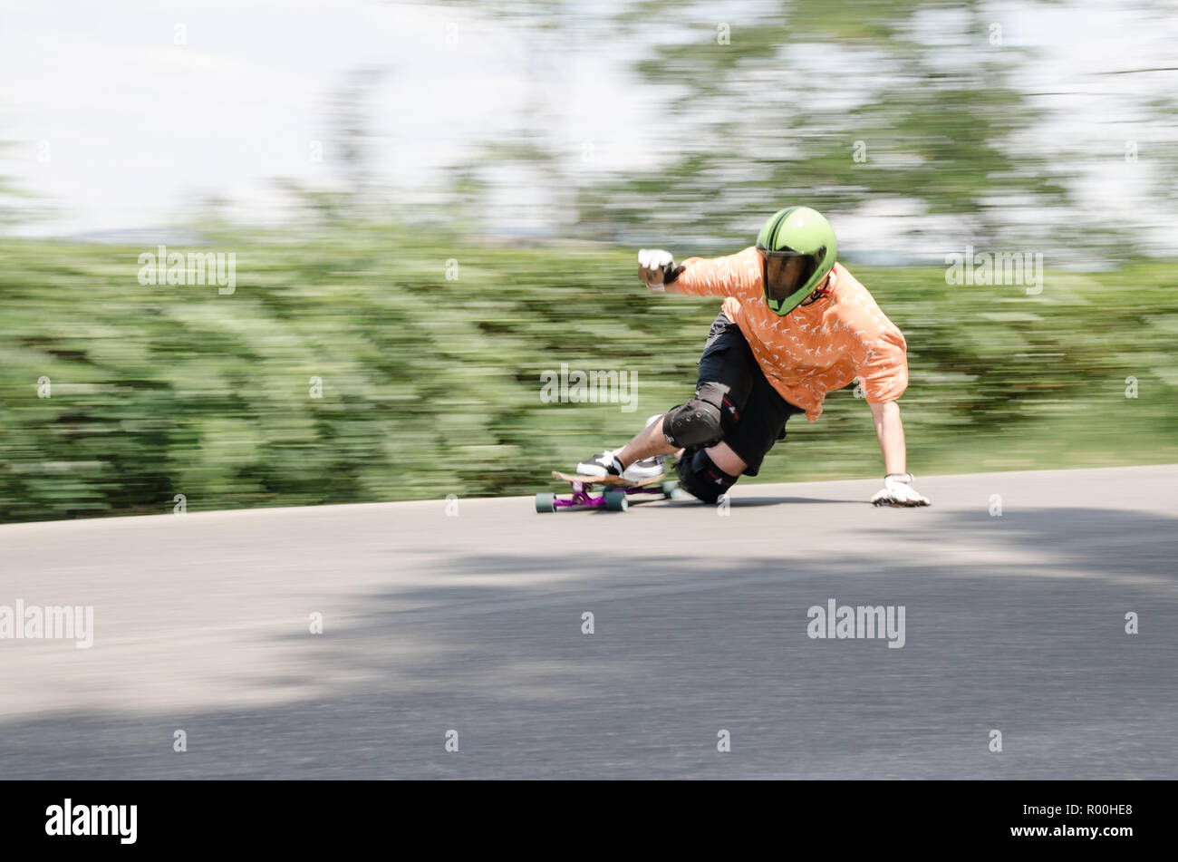 Downhill skateboarder with green helmet running down fast on the ...