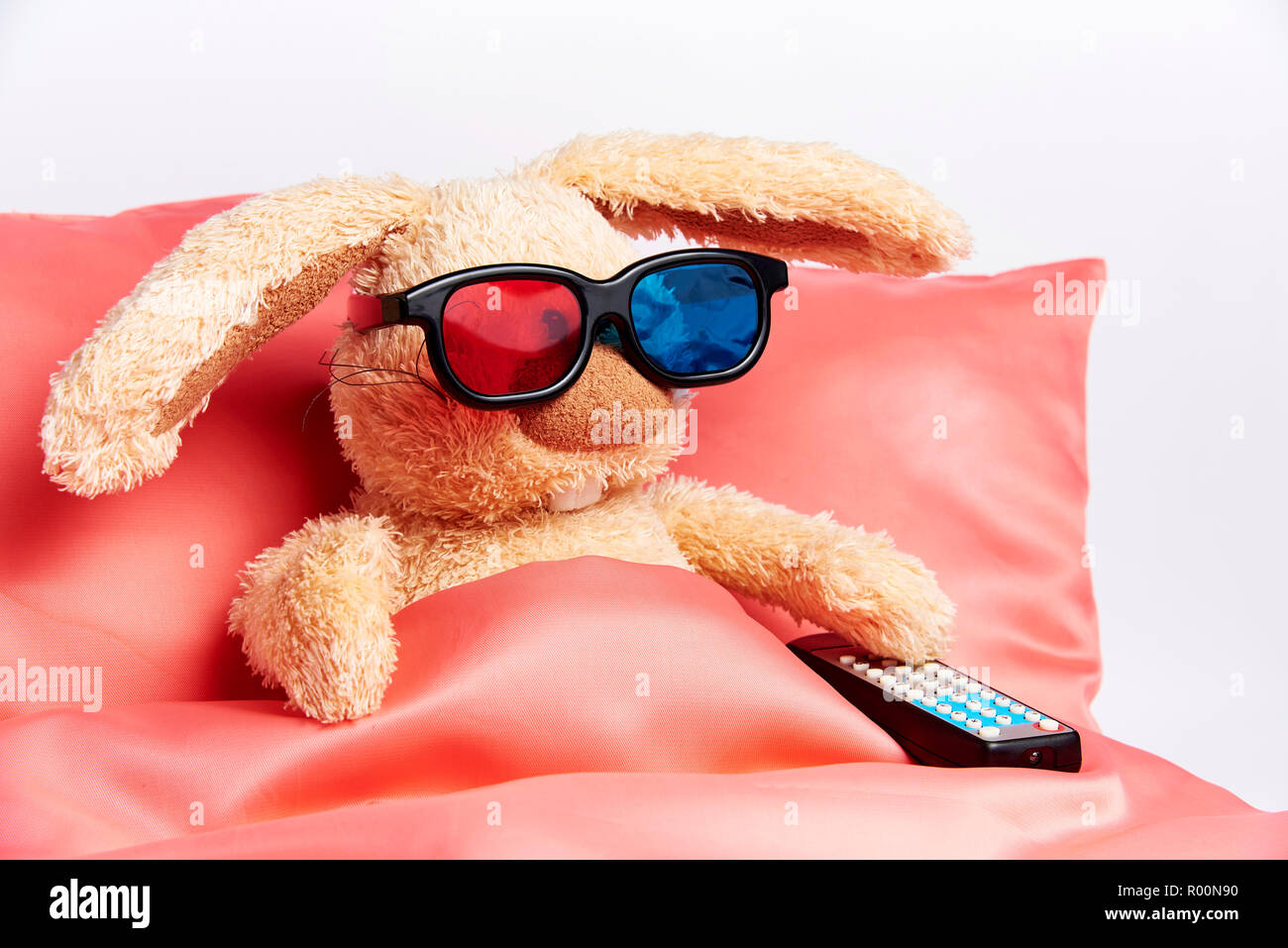 A toy rabbit in stereo glasses with a remote control from the TV lie in ...