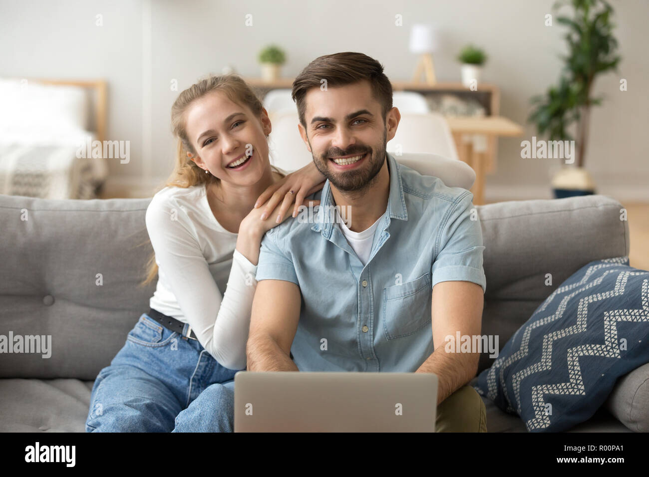 Attractive young couple using pc sitting on couch at home Stock Photo ...