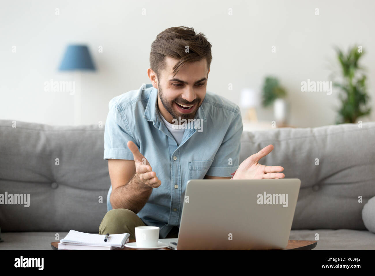 Surprised young man read news on laptop Stock Photo - Alamy