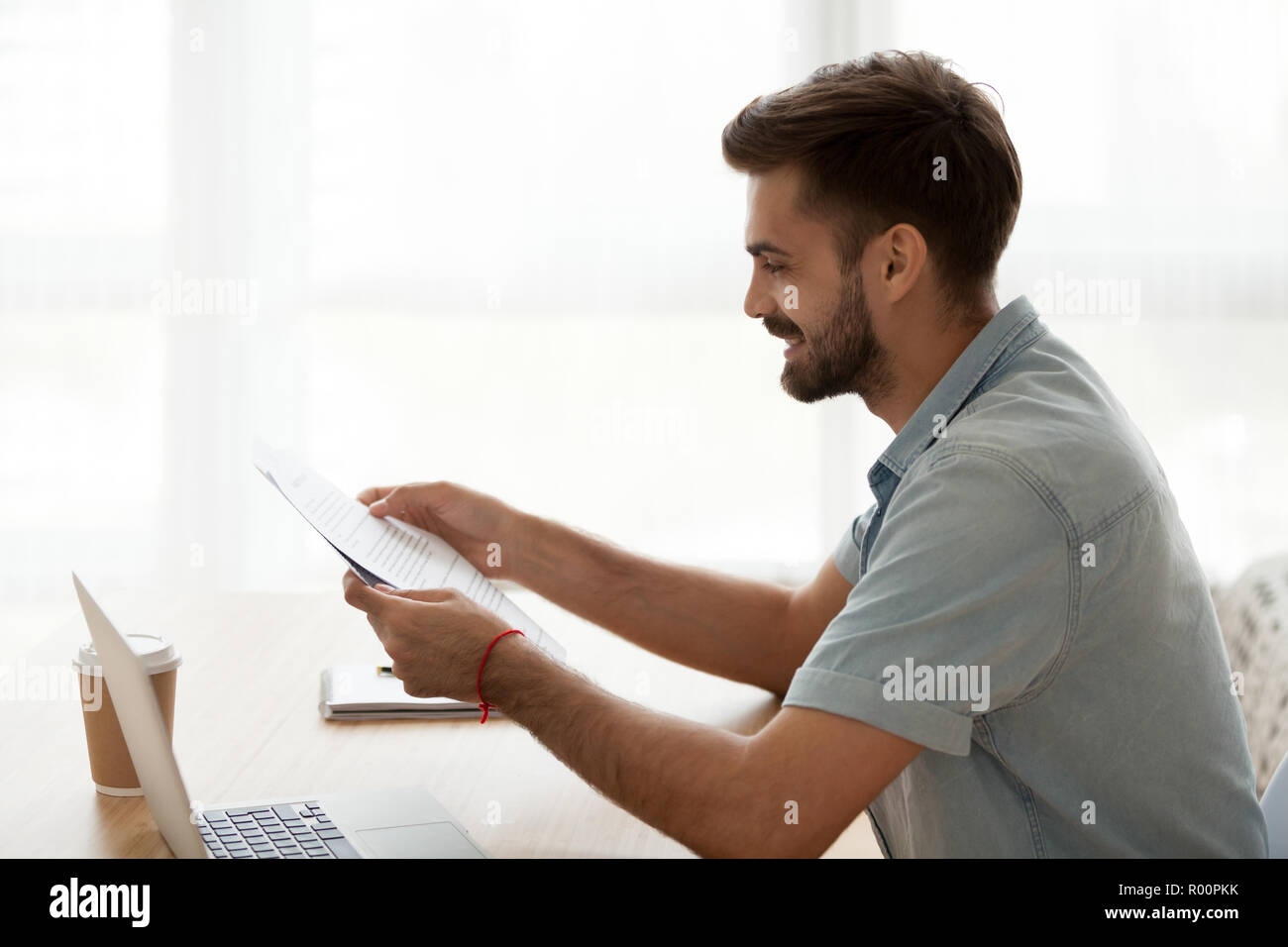 Happy man reading letter sitting at the desk Stock Photo - Alamy