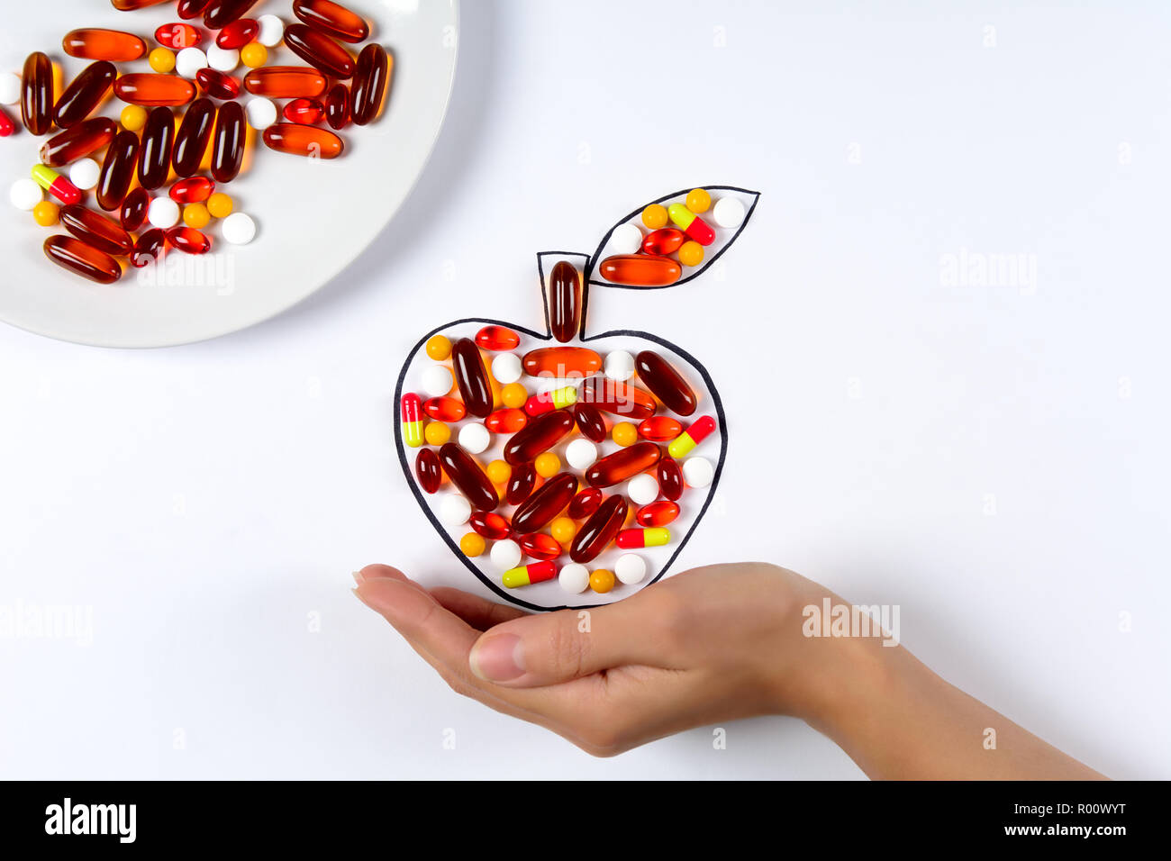 Hand holding drawing apple with colorful capsules and pills on white ...