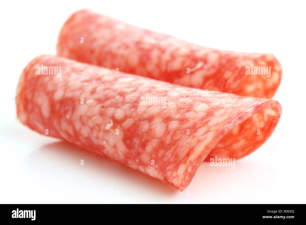 Thin slices of salami rolled into shape on white background Stock Photo ...