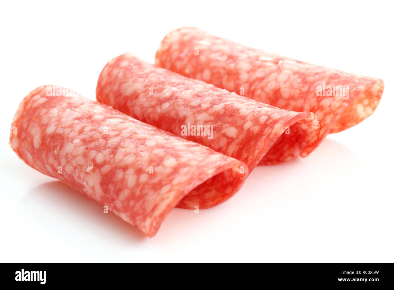 Thin slices of salami rolled into shape on white background Stock Photo ...