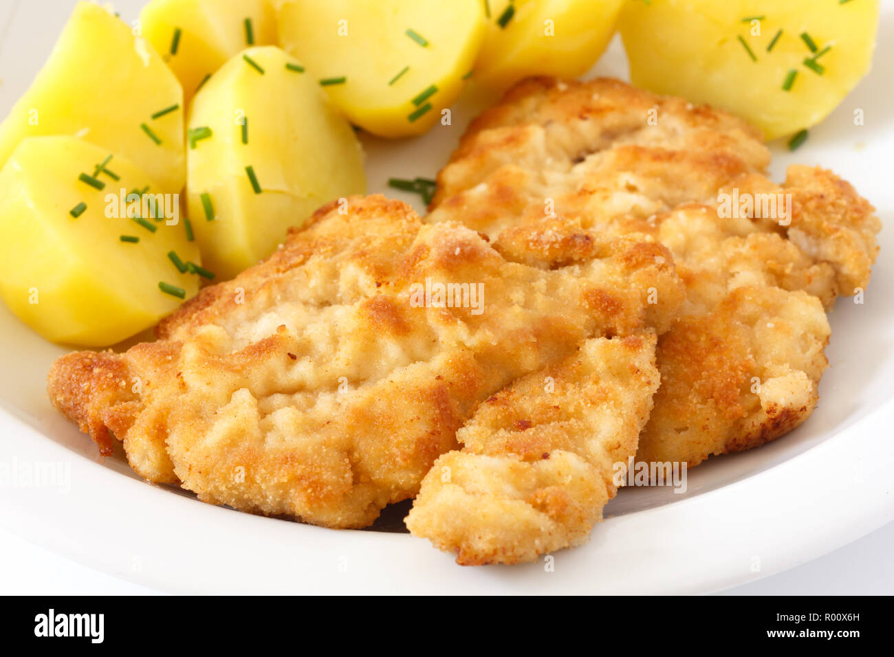 Golden fried schnitzel with boiled potatoes and chives Stock Photo - Alamy