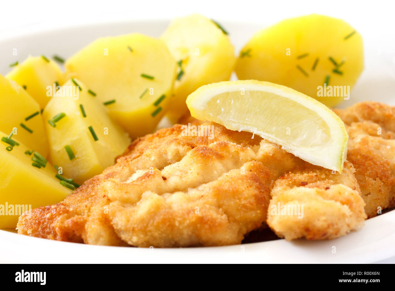 Golden fried schnitzel with boiled potatoes, chives and a slice of ...