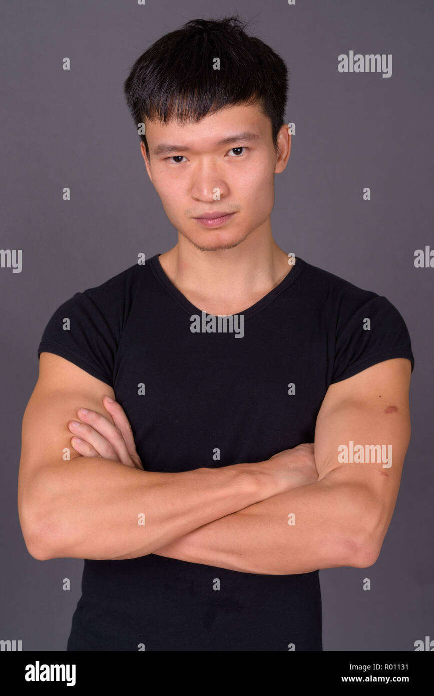 Studio shot of young Chinese man against gray background Stock Photo ...