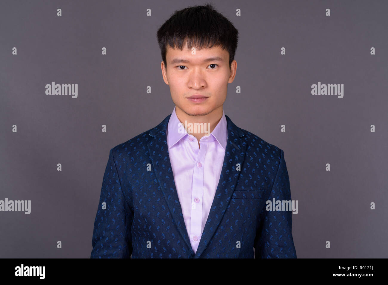 Portrait of young Chinese businessman against gray background Stock ...