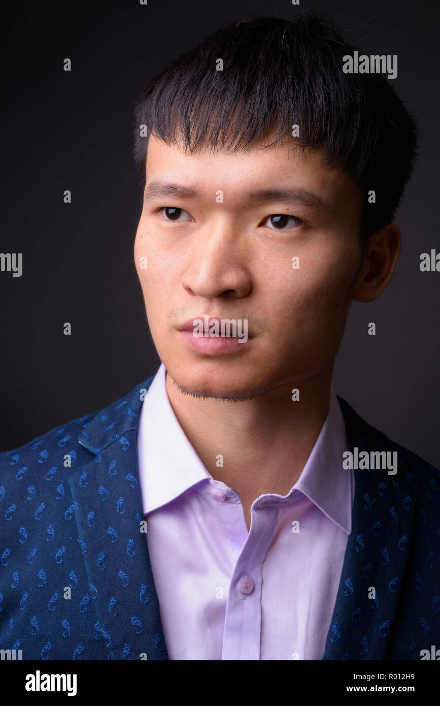 Portrait of young Chinese businessman against gray background Stock ...