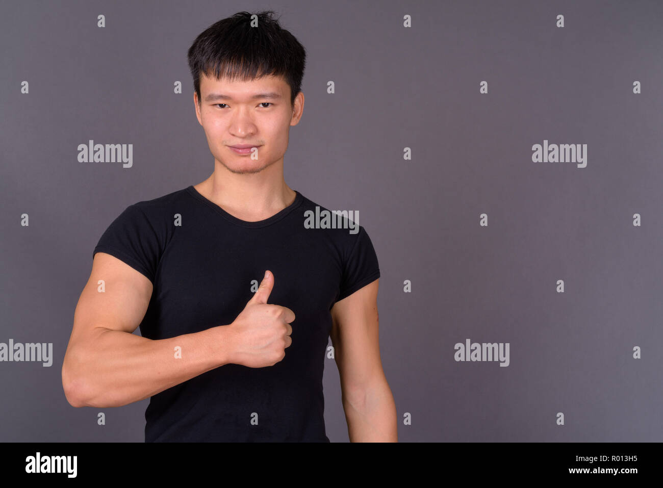 Studio shot of young Chinese man against gray background Stock Photo ...