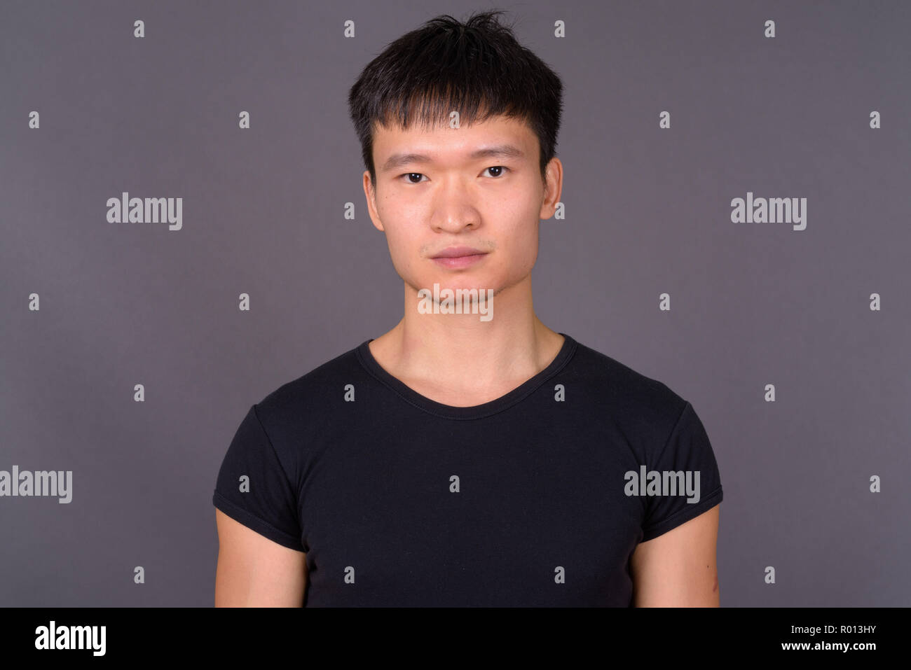 Studio shot of young Chinese man against gray background Stock Photo ...