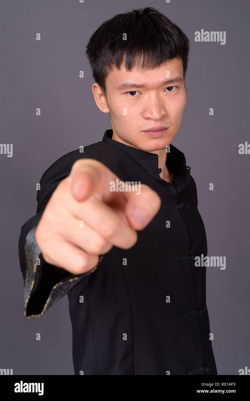 Studio shot of young Chinese man against gray background Stock Photo ...