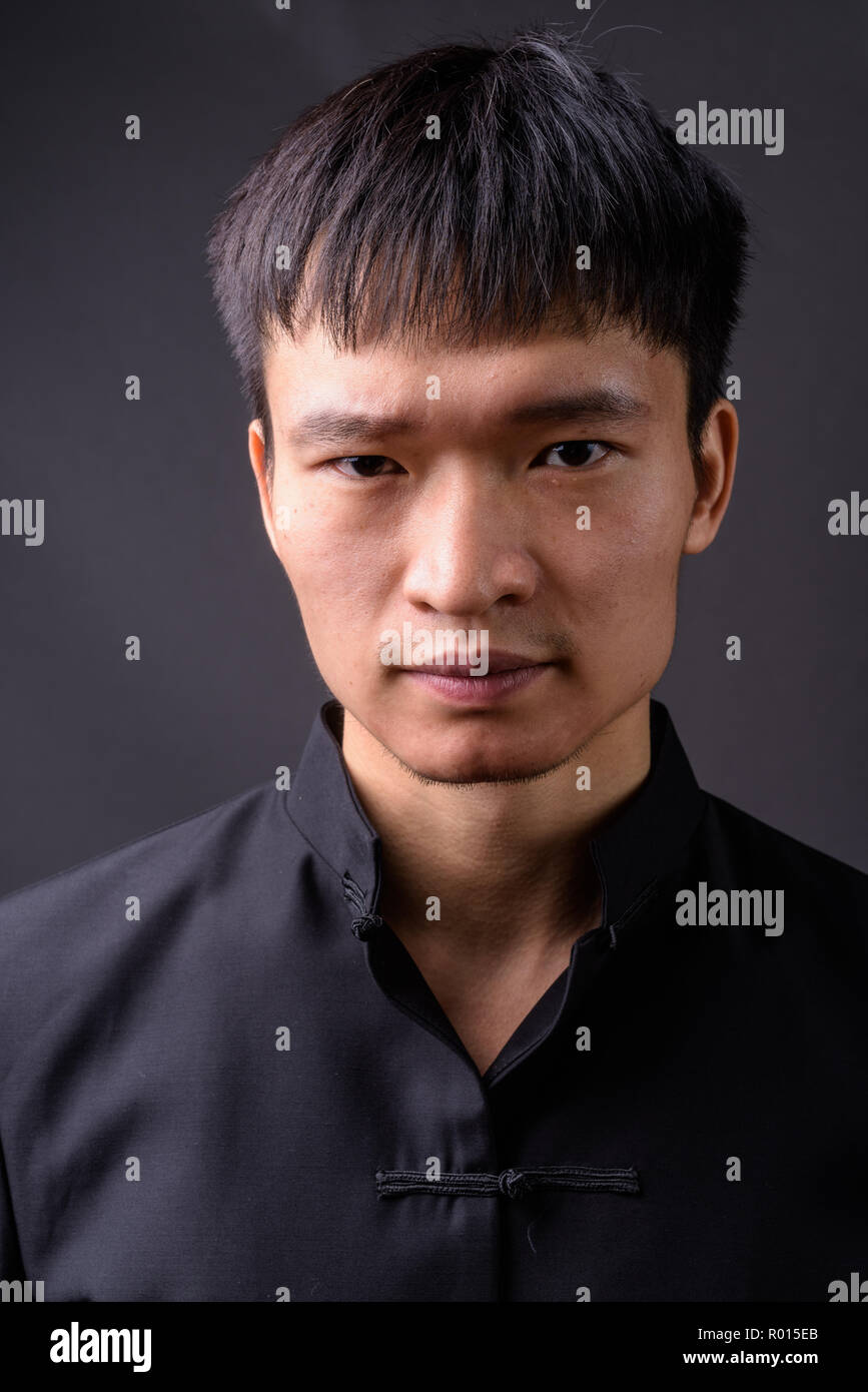 Studio shot of young Chinese man against gray background Stock Photo ...