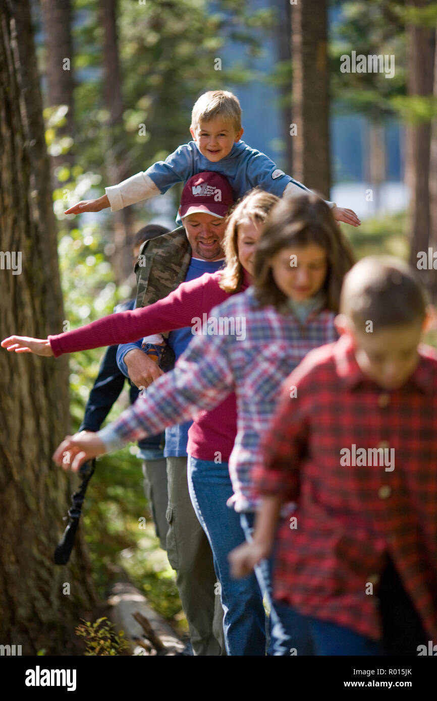 Happy family walking behind each other through a forest Stock Photo - Alamy