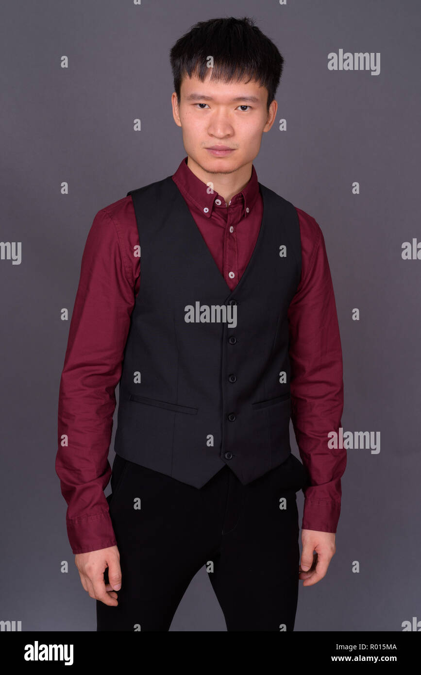 Portrait of young Chinese businessman against gray background Stock ...