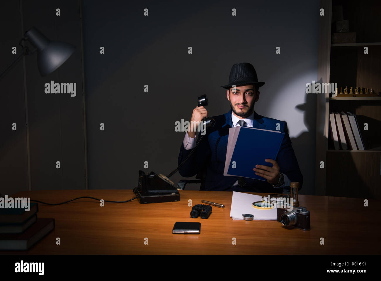 Detective sitting in dark room in vintage concept Stock Photo - Alamy