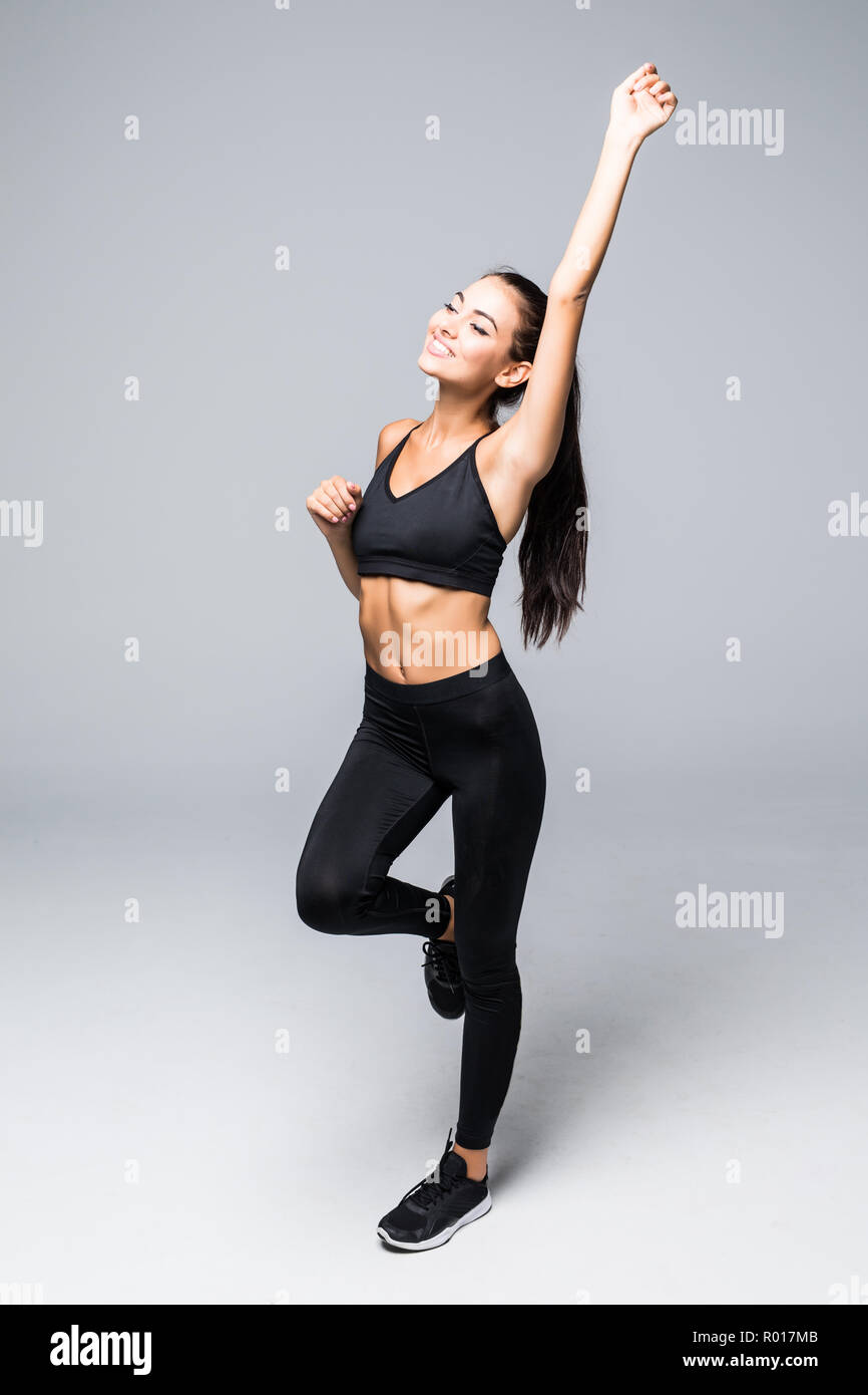Full length portrait of happy young woman with arms raised doing ...