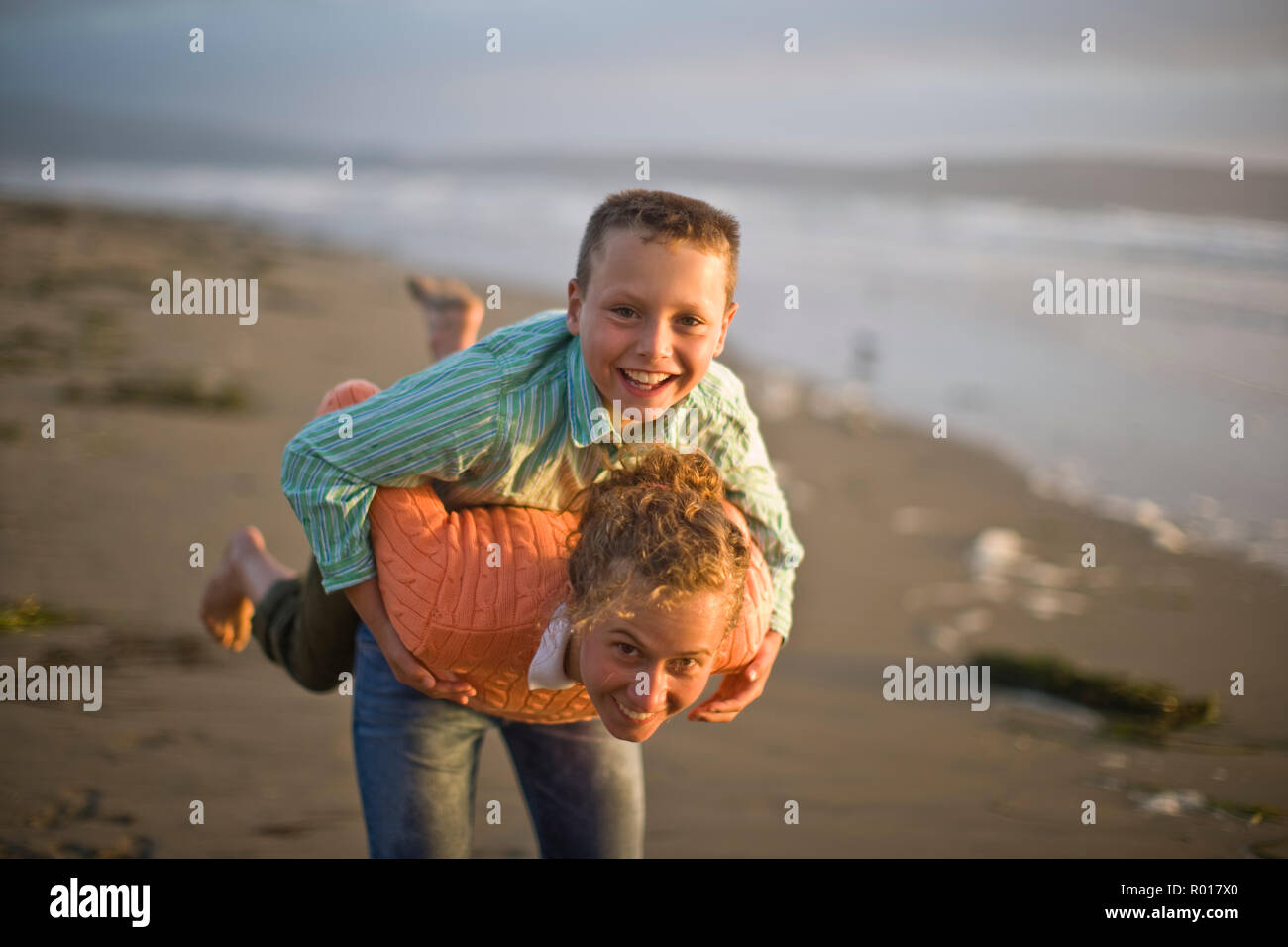Portrait of a smiling teenage girl and her younger brother giving each ...