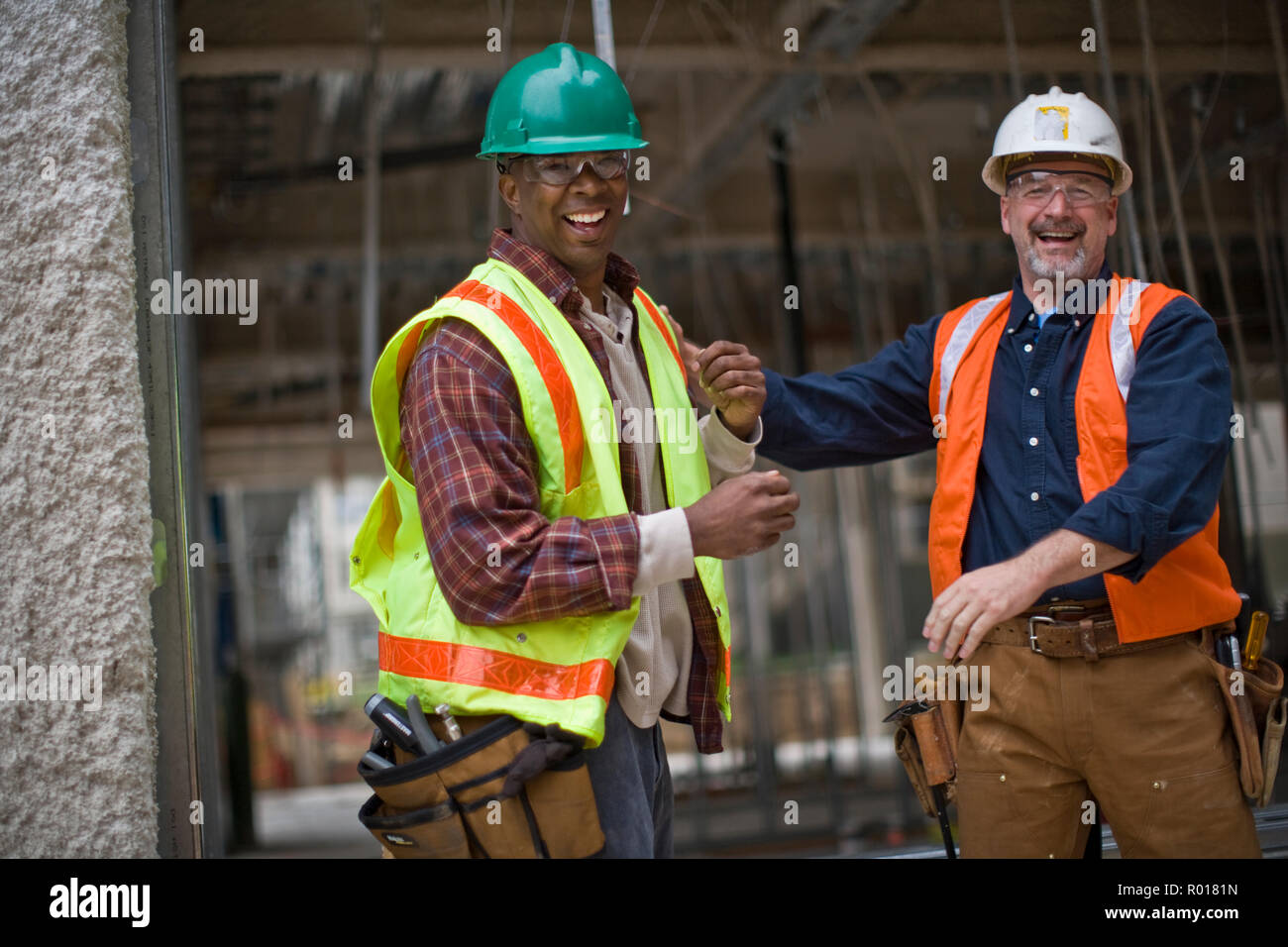 Two builders smiling on a construction site Stock Photo - Alamy