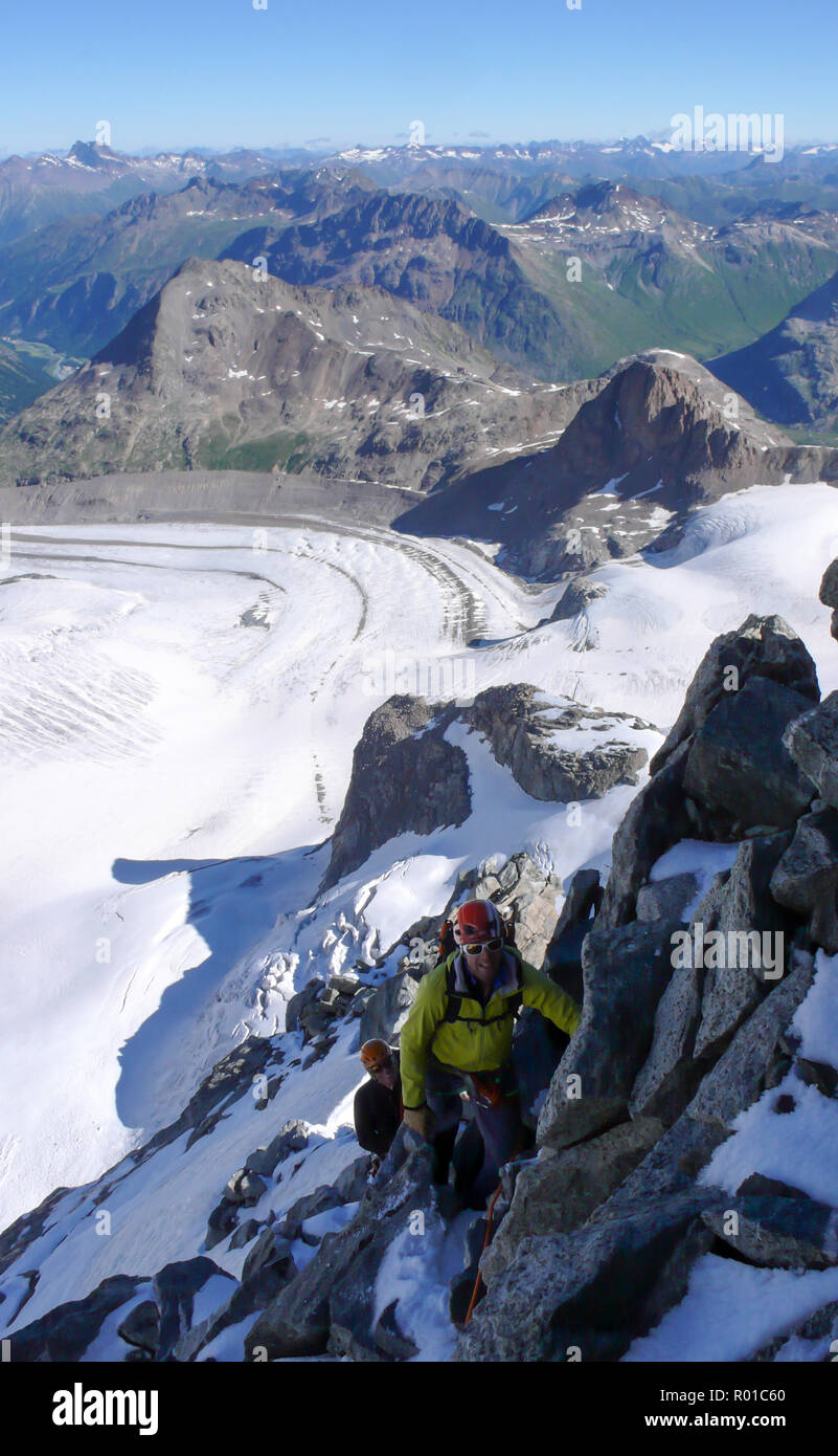 mountain guide leading male client to the summit of a high alpine peak ...