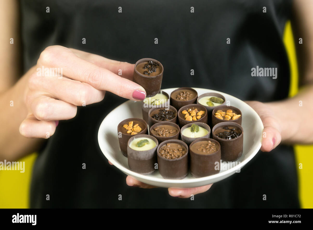 Female hands with a plate of chocolates with filling Stock Photo - Alamy