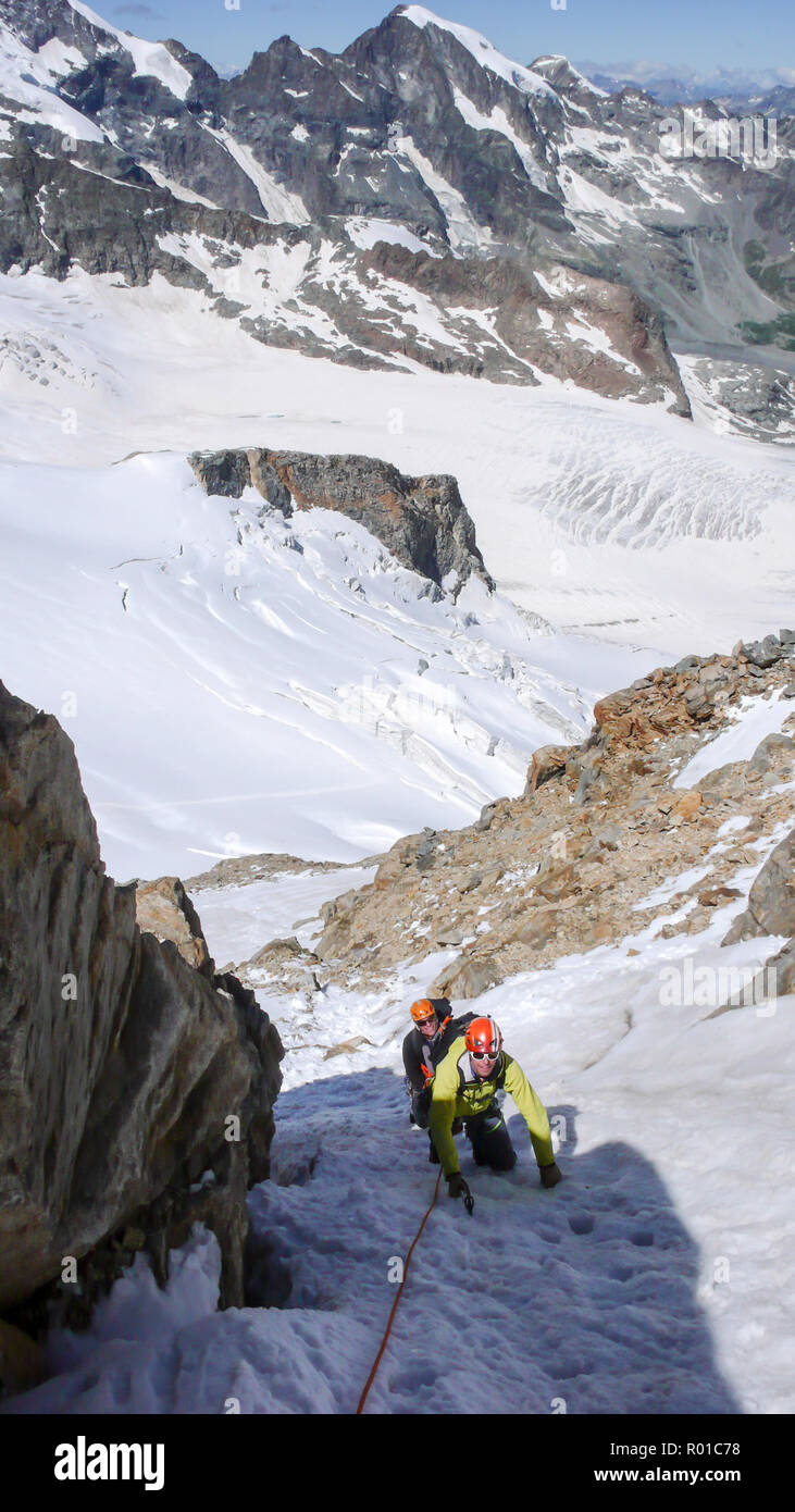 mountain guide leading male client to the summit of a high alpine peak ...