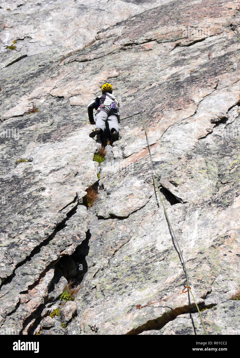 mountain guide rock climber on a steep granite route in the Alps of ...