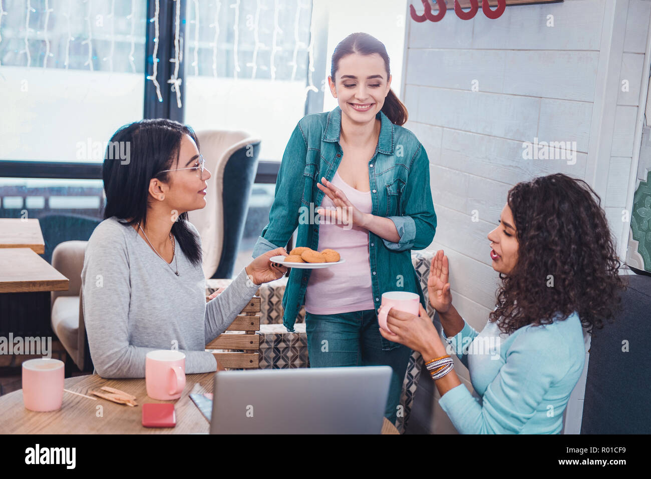 Nice positive woman offering cookies to her colleague Stock Photo - Alamy