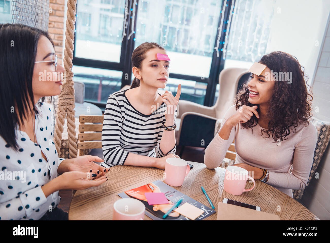 Positive nice women playing a guessing game Stock Photo - Alamy