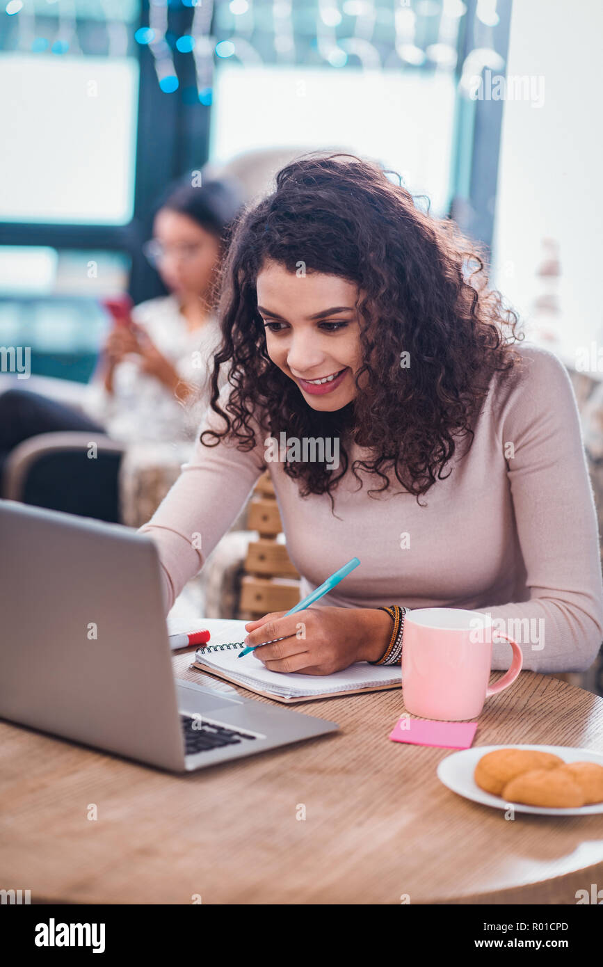 Positive nice woman taking notes in the notebook Stock Photo - Alamy