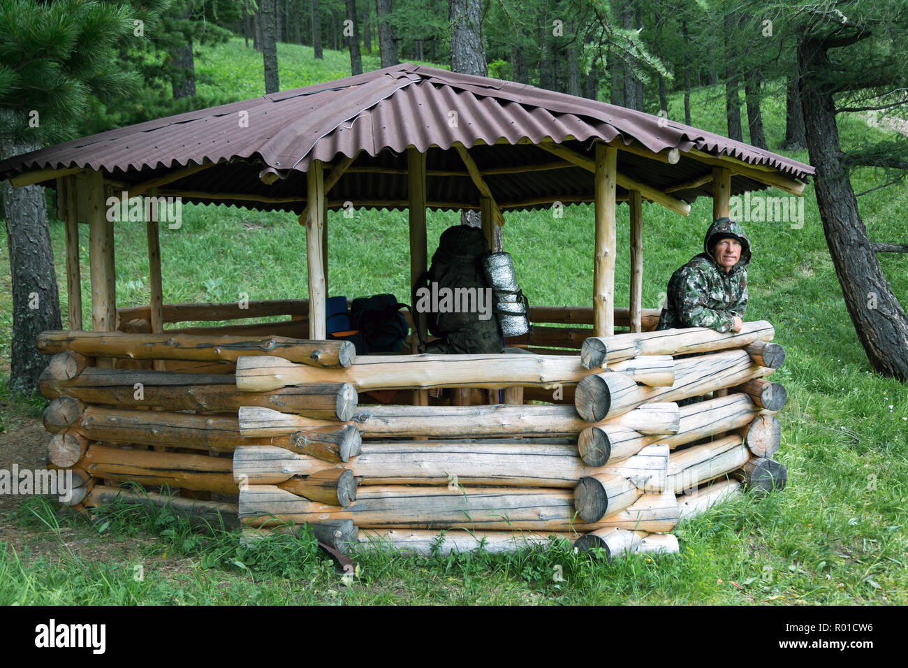 A man hides from rain and weather in a makeshift shelter of logs and ...