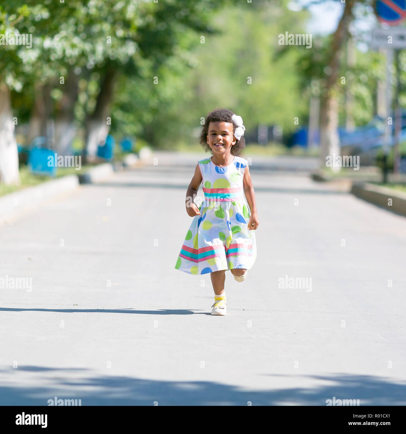 Dark-skinned little girl running along the road in the yard Stock Photo ...
