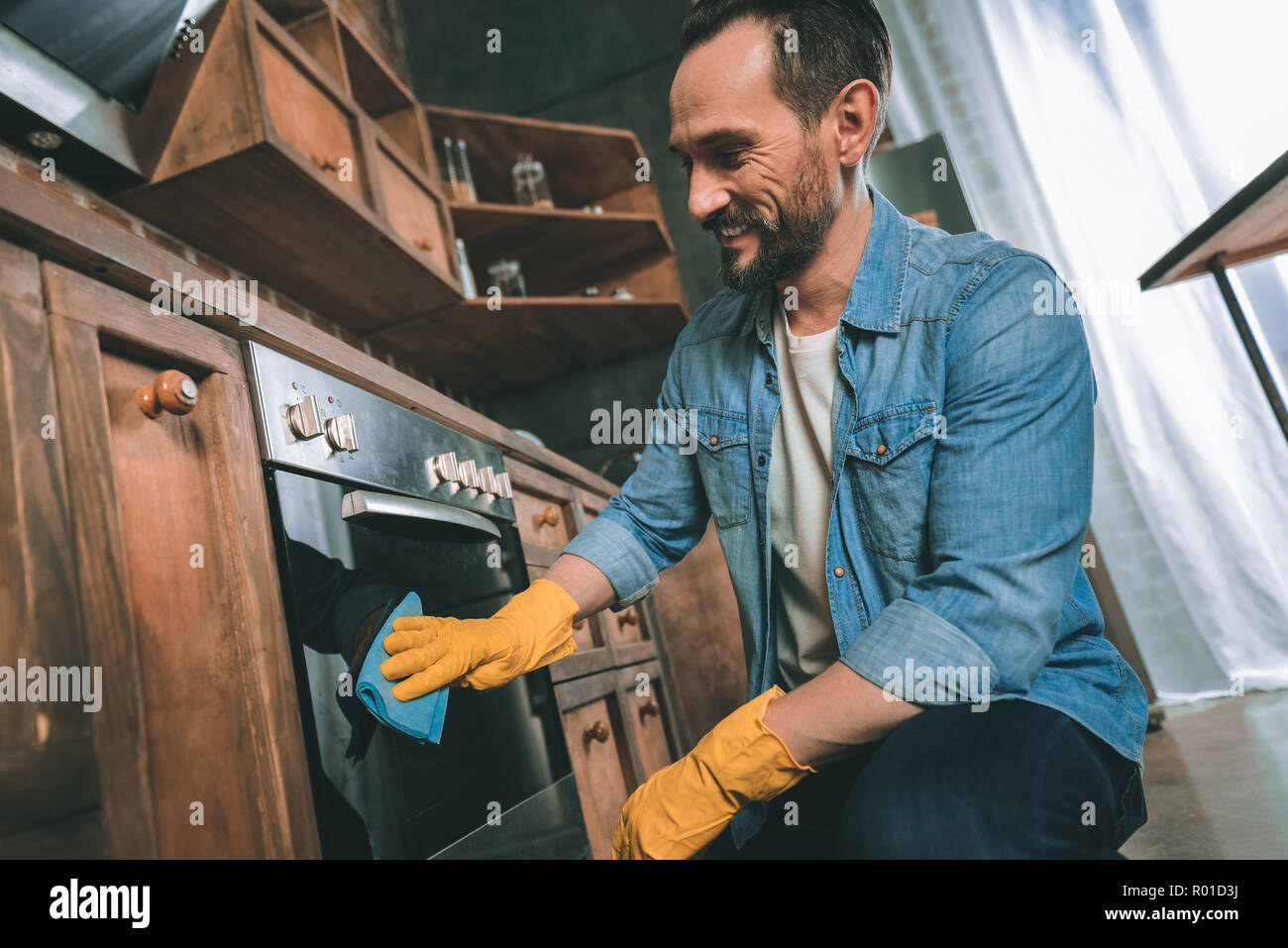 Positive delighted husband cleaning kitchen Stock Photo - Alamy